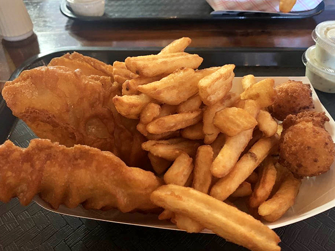 Golden-battered fish that shatters with each bite, nestled alongside a mountain of crispy fries. The holy trinity of fish, chips, and hushpuppies awaits.