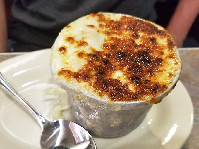 Behold the crown jewel: French onion soup with a cheese canopy that stretches like a dairy-based bungee cord. This bubbling masterpiece should require a permit. 