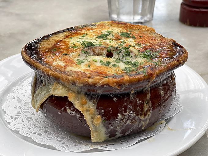 The legendary French onion soup arrives like a geological marvel &ndash; that glorious dome of bubbling, bronzed Gruy&egrave;re hiding a universe of sweet caramelized onions and rich broth below.