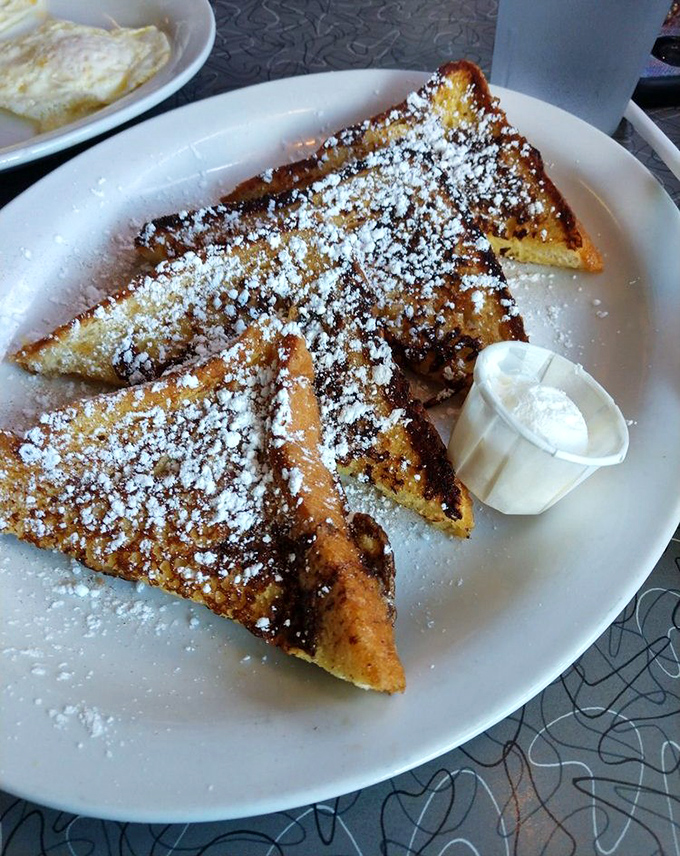 The legendary French toast arrives dusted with powdered sugar like a sweet snowfall in paradise. Worth every mile of the drive.