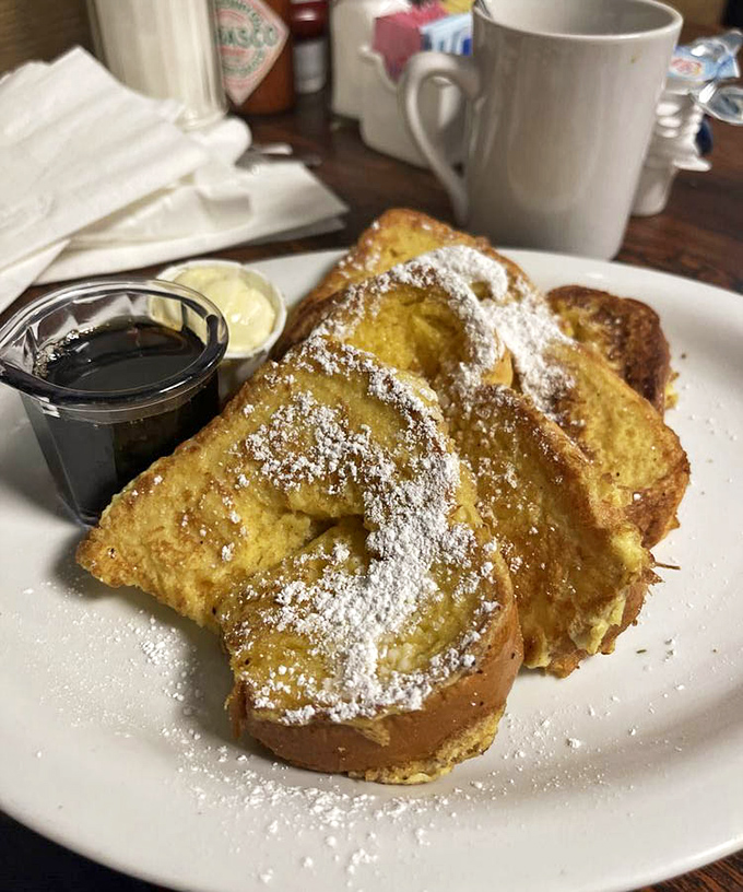 The famous French toast arrives like a golden sunrise, dusted with sweet powdered sugar dreams.