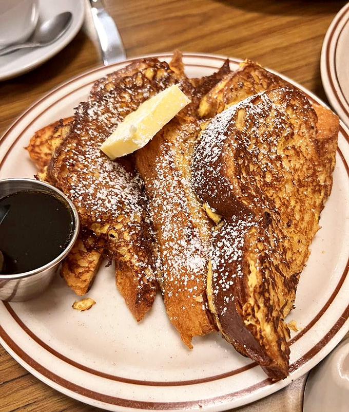 French toast that doesn't just break your diet—it shatters it with golden-brown perfection, a snowfall of powdered sugar, and maple syrup worth every sticky finger.