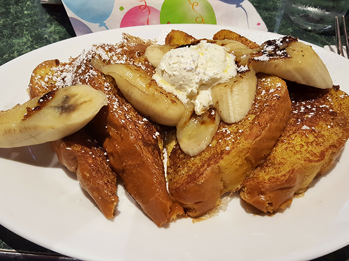 Behold the legendary French toast—golden, custard-soaked perfection topped with caramelized bananas and a cloud of whipped cream that would make Elvis swoon.