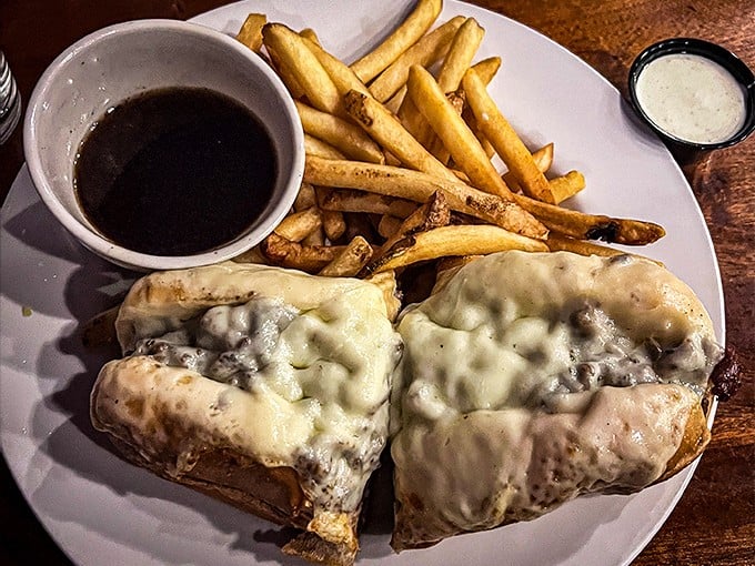 The French Dip arrives like a work of art &ndash; melted cheese cascading over tender beef, with that magical au jus waiting to transform each bite.