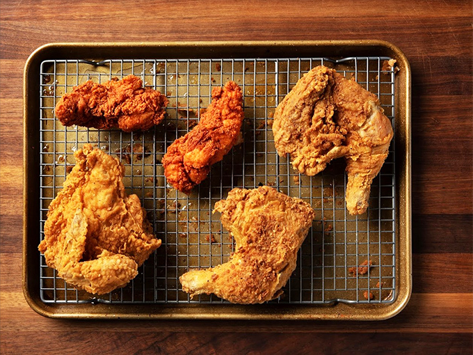Golden-brown perfection resting on a wire rack &ndash; this isn't just fried chicken, it's edible architecture with a PhD in crunchology.