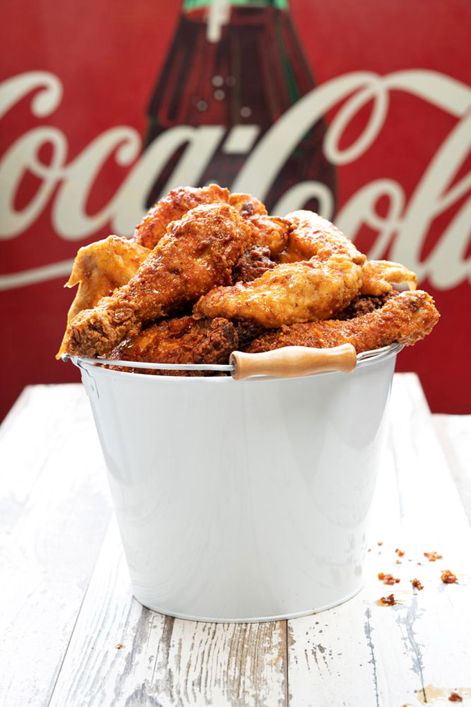 A metal bucket of golden-fried chicken perfection against a Coca-Cola backdrop. This isn't just food; it's edible art.