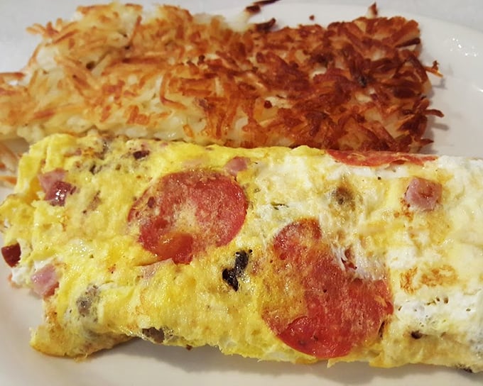 This isn't just any omelet &ndash; it's breakfast architecture at its finest. Golden-brown hash browns stand guard beside eggs studded with savory treasures.