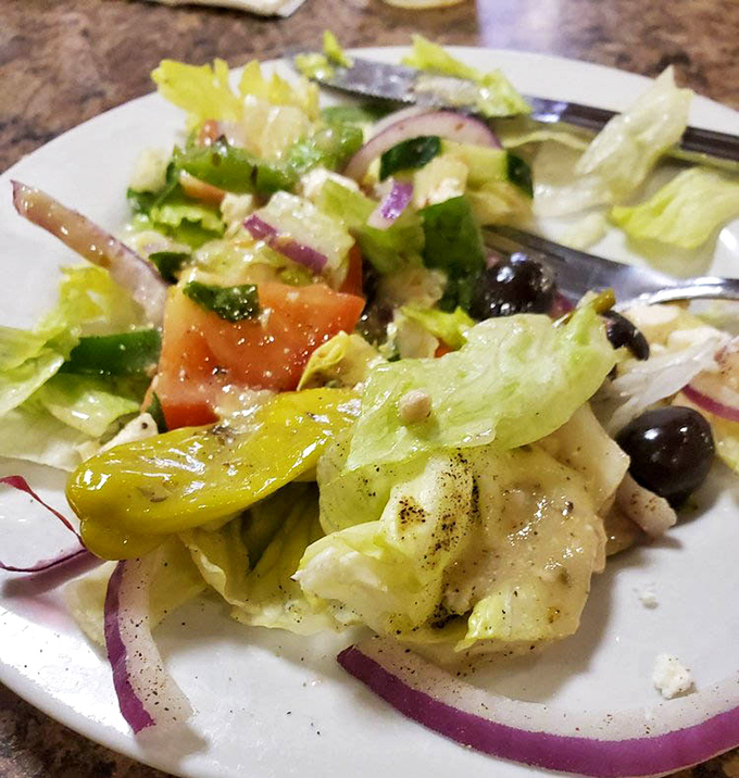 The Greek salad in all its glory &ndash; crisp lettuce, vibrant tomatoes, purple onions, and olives playing supporting roles to the star: chunks of authentic feta.