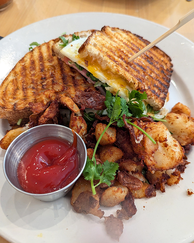 This isn't just a sandwich—it's a grilled masterpiece with a perfectly runny egg and those breakfast potatoes that somehow stay crispy until the last bite.