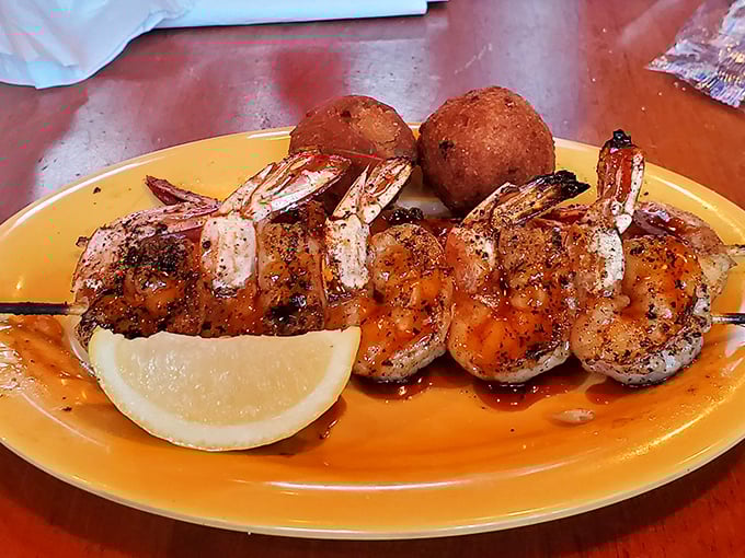 Perfectly grilled shrimp skewers with a hint of char, accompanied by golden hushpuppies and a lemon wedge &ndash; simplicity that lets the Gulf's bounty shine.