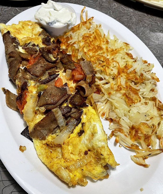 Behold the star attraction: the gyro omelet in all its glory, flanked by hash browns so perfectly crisp they deserve their own fan club.