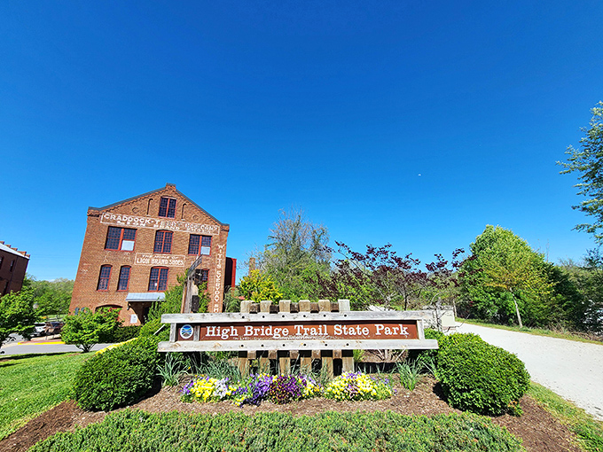The entrance to High Bridge Trail State Park promises adventure with its rustic sign and historic brick building backdrop&mdash;no Instagram filter required for this natural beauty.