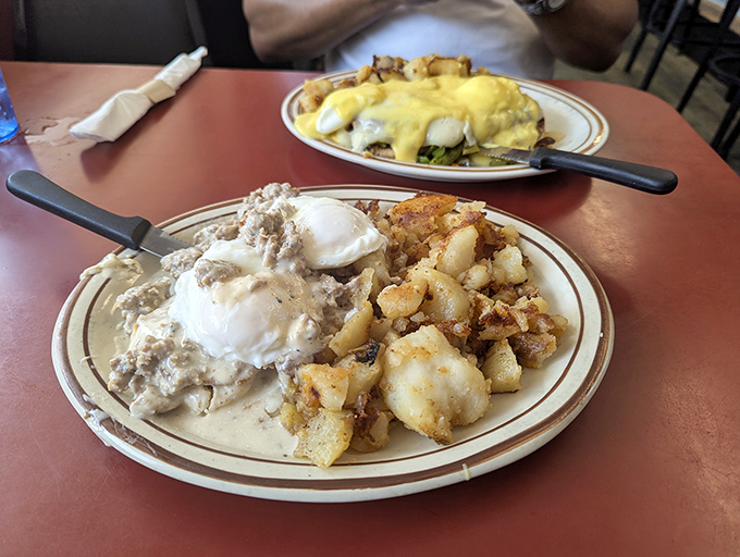 Behold the holy trinity of diner perfection: creamy sausage gravy, perfectly poached eggs, and those legendary home fries that could make a potato farmer weep.