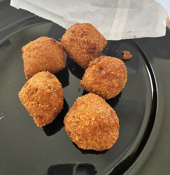 Golden-brown hush puppies with that perfect crispy exterior hiding a tender, savory interior &ndash; these little cornmeal spheres of joy are worth the trip alone.