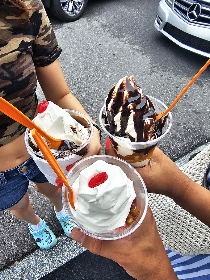 Three cups of pure joy, where hot fudge cascades over vanilla soft-serve like a chocolate waterfall from Willy Wonka himself.