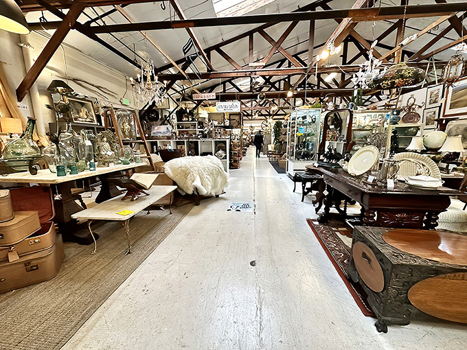 Exposed wooden beams create a cathedral-like space for vintage worship, where chandeliers dangle above carefully arranged vignettes of furniture and collectibles.