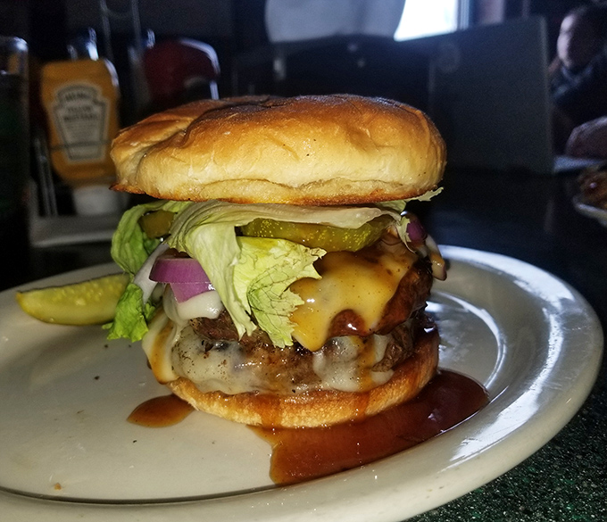 This isn't just a burger; it's a skyscraper of flavor with melty cheese cascading down like a yellow waterfall of happiness.
