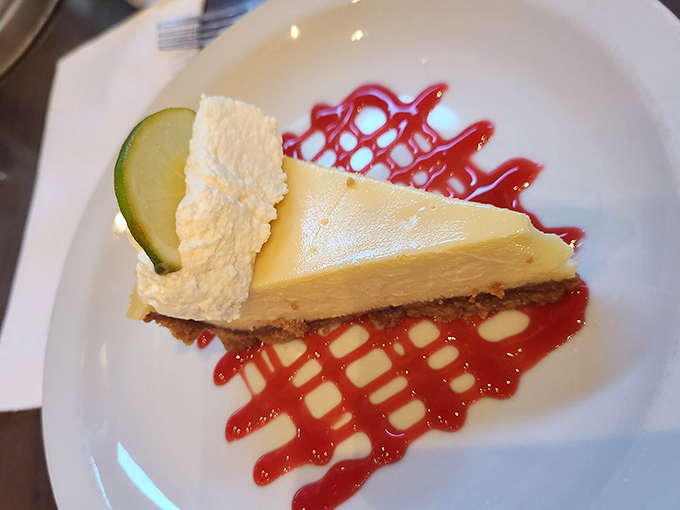 The legendary key lime pie arrives like a celebrity &ndash; perfectly tart-sweet filling, buttery graham cracker crust, and that artistic raspberry drizzle.