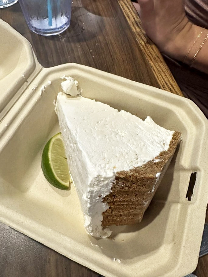 The key lime pie arrives like a cloud on a graham cracker throne, with that perfect pale yellow hue that screams authenticity.