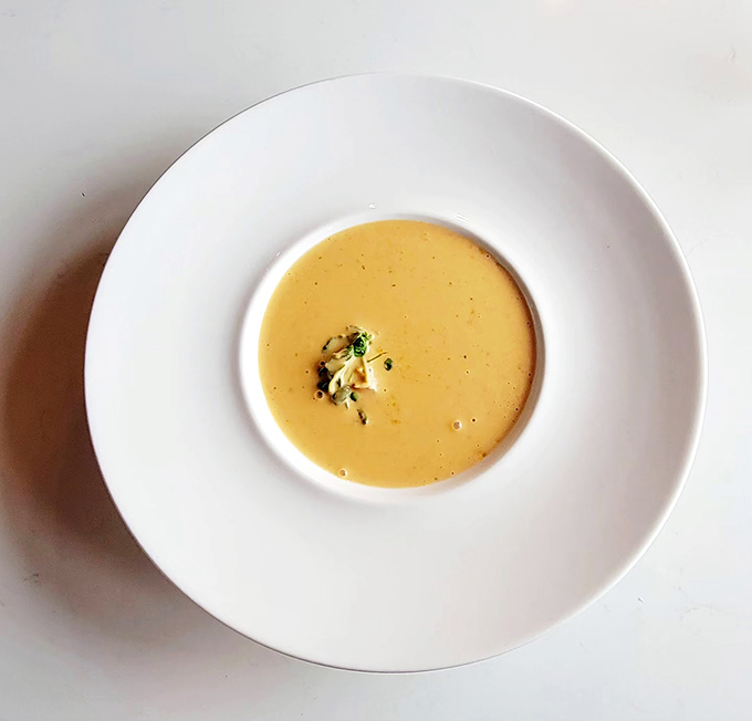 The legendary lobster bisque arrives like liquid gold in a porcelain frame, garnished with herbs that whisper, "Yes, the drive was worth it."