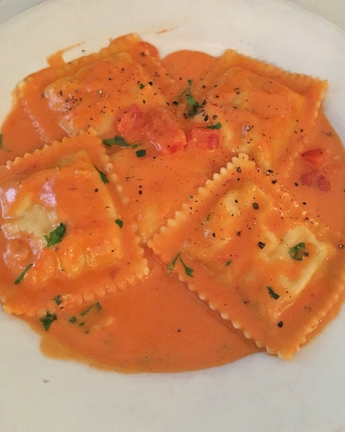 The infamous lobster ravioli, bathed in that sunset-colored cognac sauce, makes first-timers gasp and regulars smile knowingly.