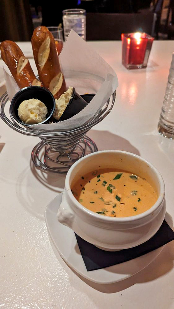 The legendary lobster bisque arrives like a sunset in a bowl, accompanied by pretzel breadsticks that are merely vehicles for more butter.
