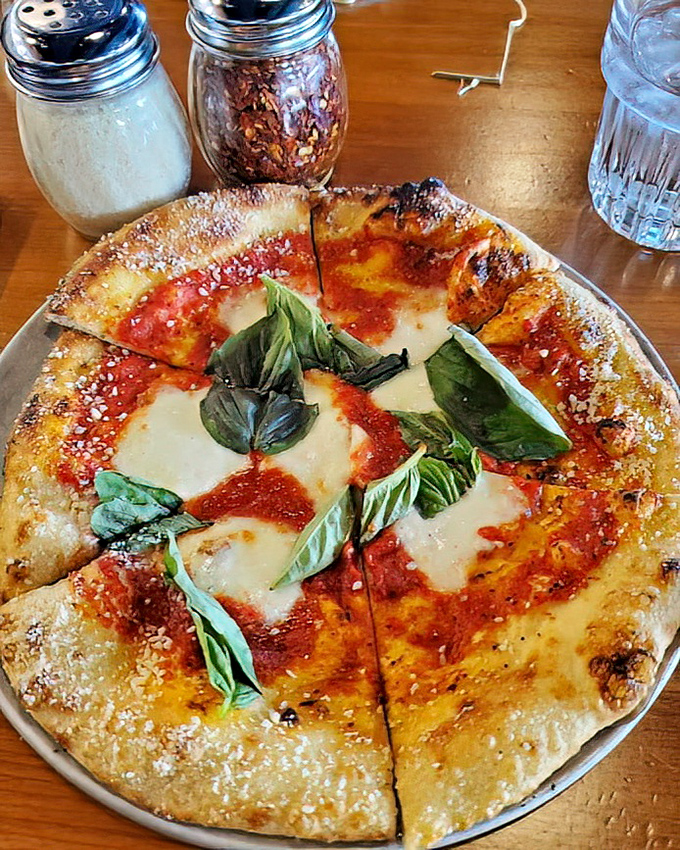 Behold the Margherita pizza in all its glory—where simplicity becomes art with bubbling mozzarella, vibrant tomato sauce, and fresh basil dancing across a perfectly charred crust.