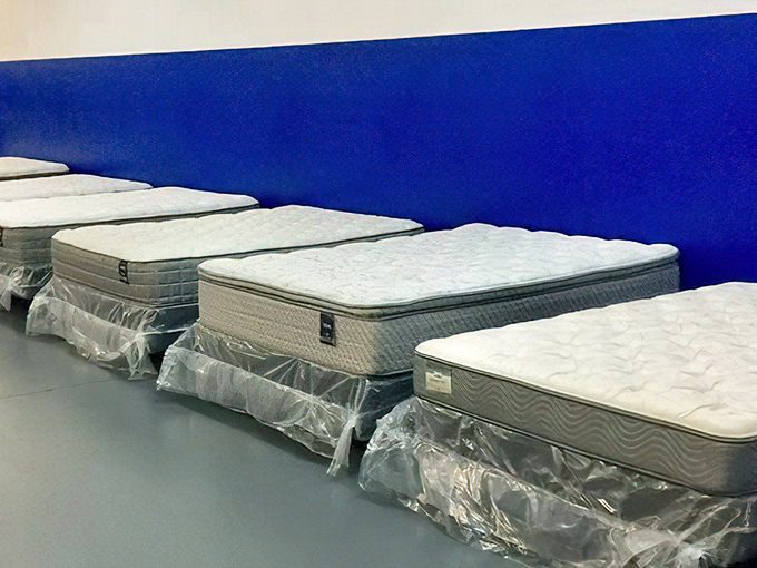 Sleep tight without emptying your wallet could be the slogan for this impressive lineup of nearly-new mattresses against that bold blue wall.