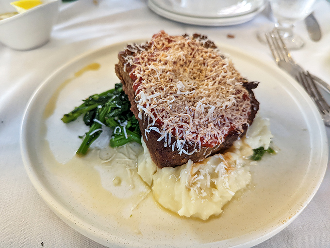 Not just meatloaf, but a masterpiece &ndash; crowned with cheese and nestled on cloud-like mashed potatoes with vibrant greens for balance.