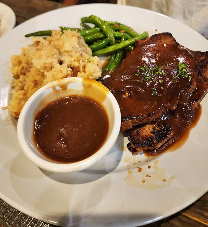 Behold the star attraction: meatloaf bathed in rich gravy alongside cloud-like mashed potatoes and vibrant green beans. Comfort food nirvana achieved.