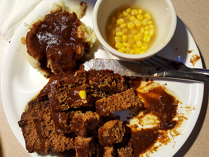 Behold the legendary meatloaf in all its glory &ndash; thick slices bathed in rich gravy alongside mashed potatoes and corn. Grandma would approve, then ask for the recipe.