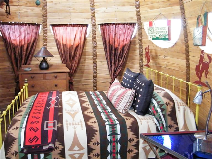 Inside, the bedroom continues the organic theme with curved wooden posts and Southwestern-inspired textiles creating a cozy forest retreat.