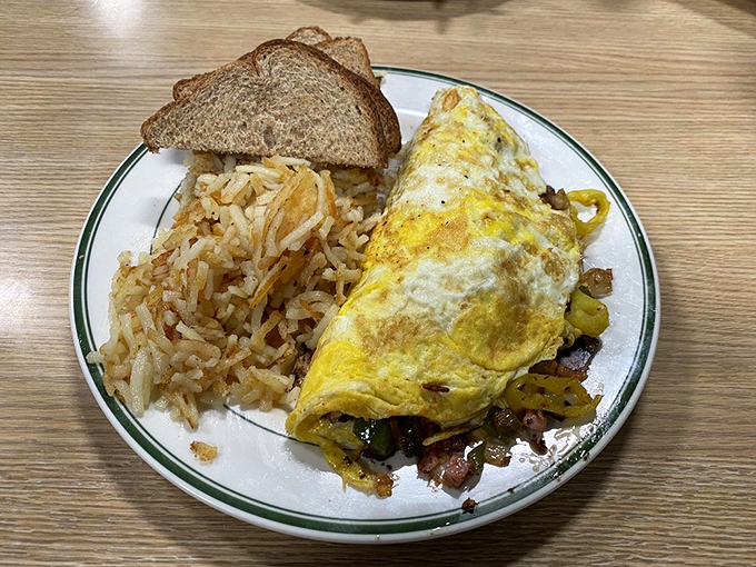 Behold the art of the perfect omelet—fluffy egg exterior giving way to a treasure trove of fillings, with hash browns standing by for moral support.