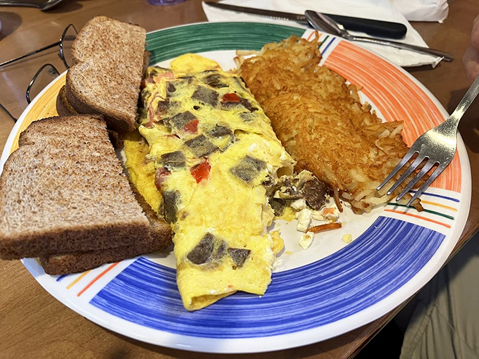 A properly executed omelet is culinary poetry&mdash;this one tells a story of perfectly cooked eggs embracing savory fillings alongside crispy hash browns.