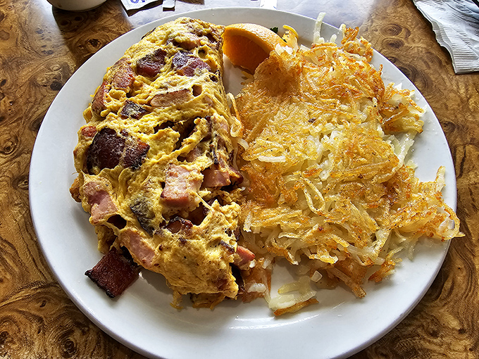 This isn't just an omelet; it's a masterclass in egg architecture with perfectly crispy hash browns standing guard. Breakfast perfection on a plate. 