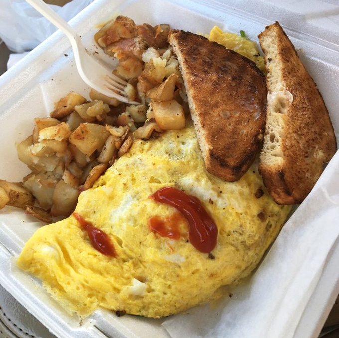 Behold the perfect omelet in its natural habitat – fluffy, golden, and accompanied by home fries that could make a potato farmer weep with joy.