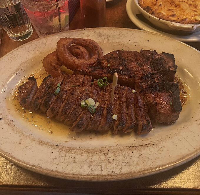 Behold the star of the show: a perfectly seared ribeye that's been pampered more than most celebrities, complete with a crispy onion ring crown.