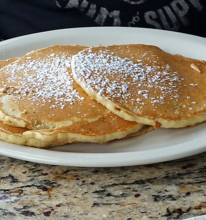 Golden pancakes dusted with powdered sugar prove that sometimes perfection comes in simple, fluffy packages.