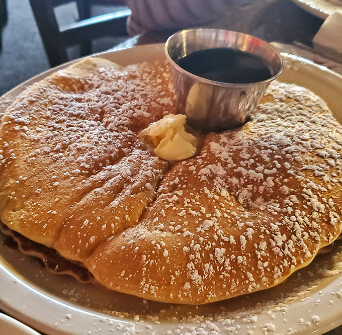 This golden pancake, dusted with powdered sugar and crowned with a pat of butter, isn't just breakfast&mdash;it's edible sunshine on a plate.