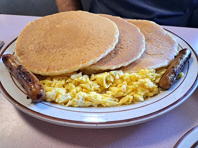 Three pancakes that could double as manhole covers, with sausages standing guard like crispy sentinels.
