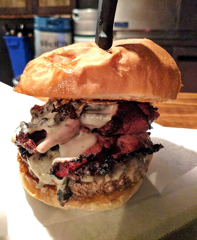 Behold the pastrami burger in all its glory—where beef meets beef's sophisticated cousin in a tower of meaty magnificence.