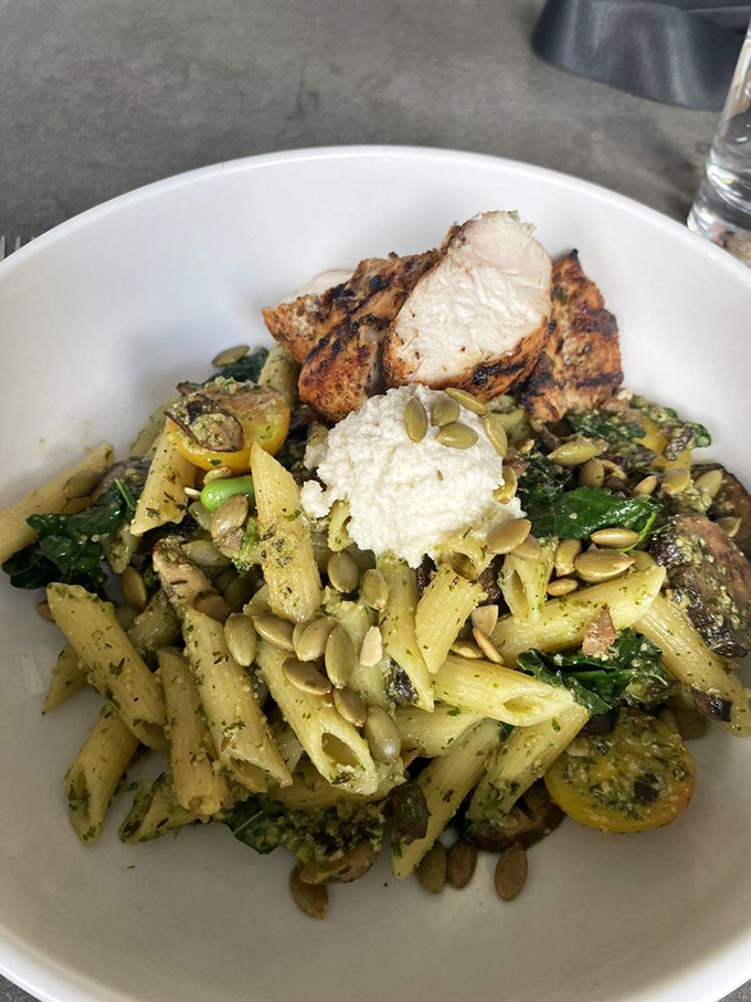 That legendary pesto pasta arrives looking like edible artwork topped with perfectly grilled protein.