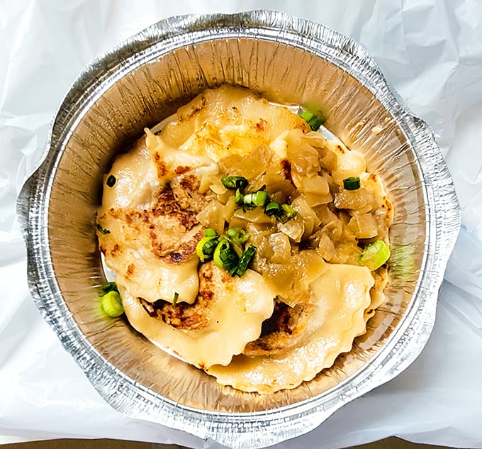 Golden perfection arrives topped with caramelized onions, proving that simple ingredients can create pure magic on a plate.