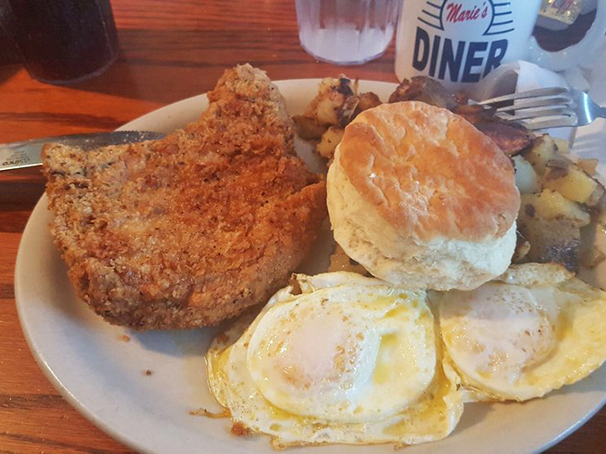 Behold the star of the show! This country-fried pork chop arrives with perfect eggs, home fries, and a biscuit that would make your grandmother both proud and jealous.