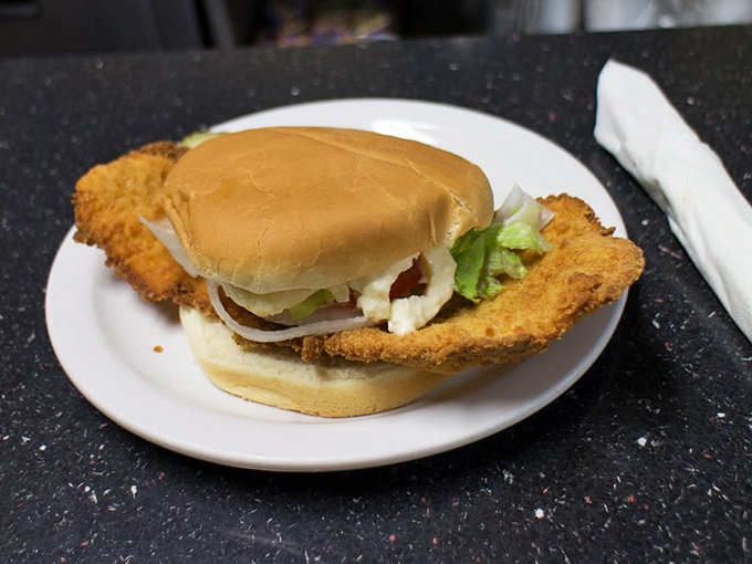 The legendary pork tenderloin sandwich in all its glory—a golden-fried masterpiece that refuses to be contained by mere bread laws.