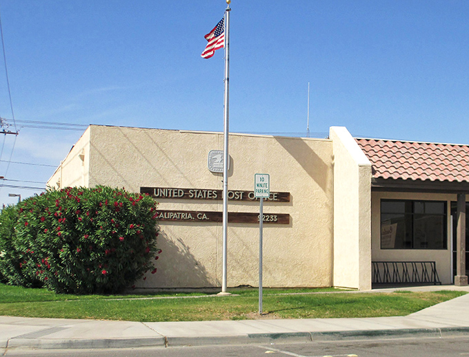 Calipatria's post office stands as a humble civic anchor, its American flag a reminder that mail service connects even the most remote communities to the wider world.