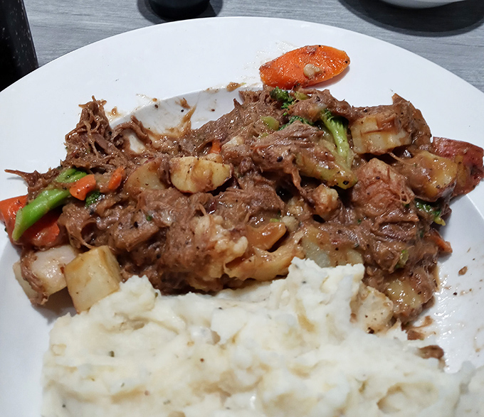 The legendary pot roast in all its glory &ndash; fork-tender beef swimming in rich gravy alongside perfectly cooked vegetables. Resistance is futile.