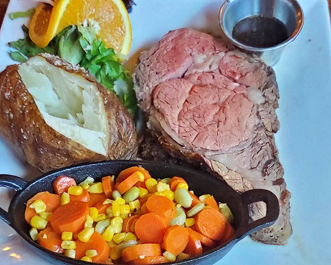 This isn't just prime rib—it's a masterpiece of meat, perfectly pink and paired with a loaded baked potato and colorful vegetable medley.
