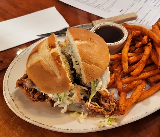 A proper pulled pork sandwich requires structural engineering skills and multiple napkins. This masterpiece comes with sweet potato fries that deserve their own fan club.
