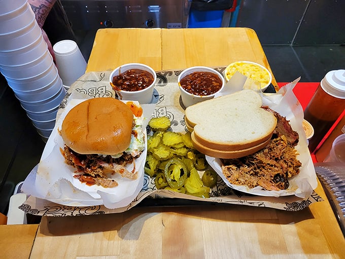 Behold the pulled pork sandwich in its natural habitat – tender strands of smoky pork nestled on a bun with pickles standing guard.